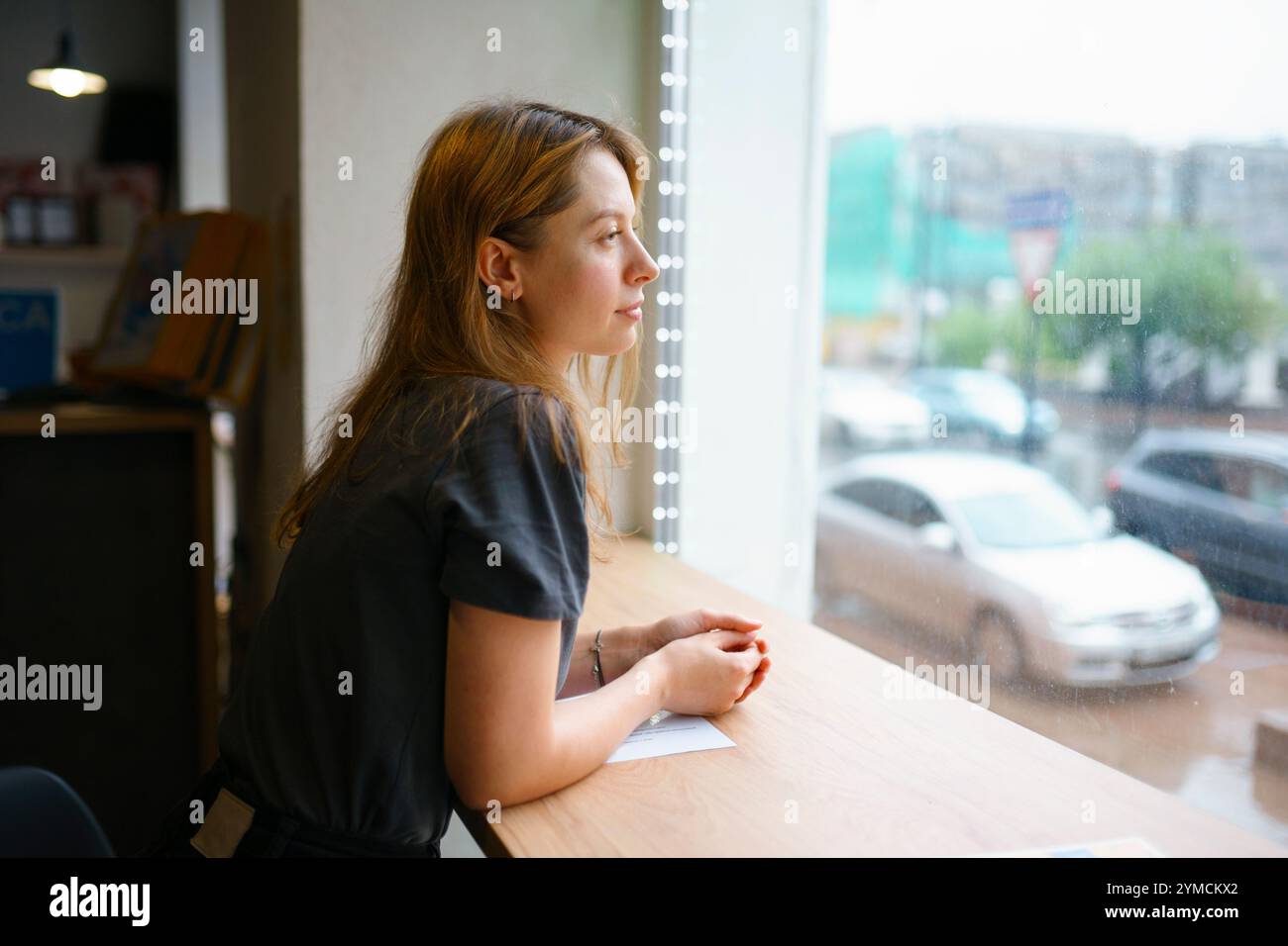 Woman leaning on window sill and looking through window Stock Photo - Alamy
