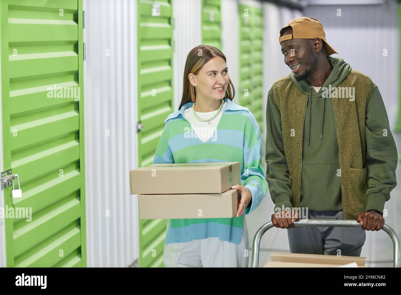 Medium shot of cheerful African American man pushing dolly cart walking ...