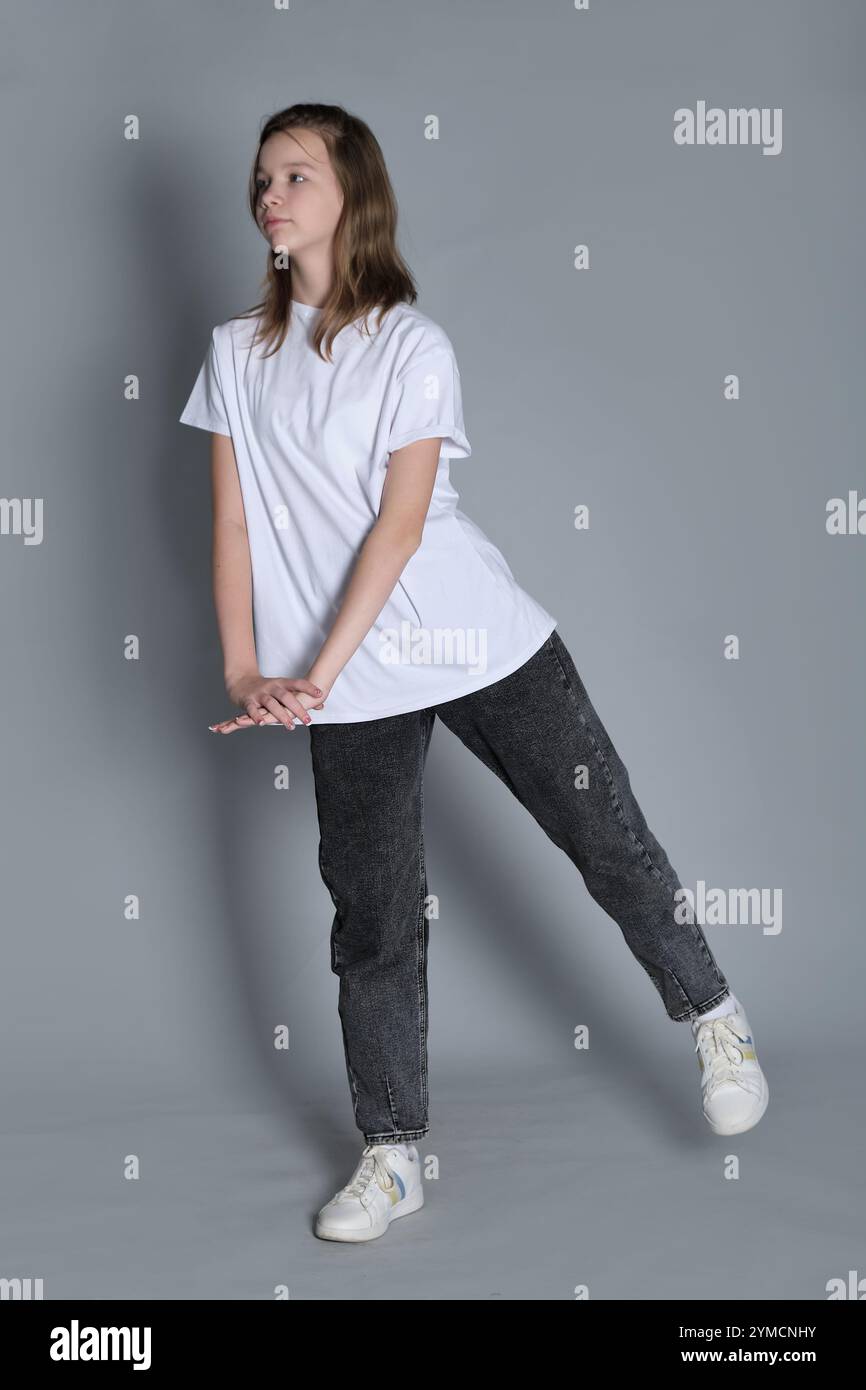 A girl poses in a relaxed stance, leaning slightly while dressed in a ...