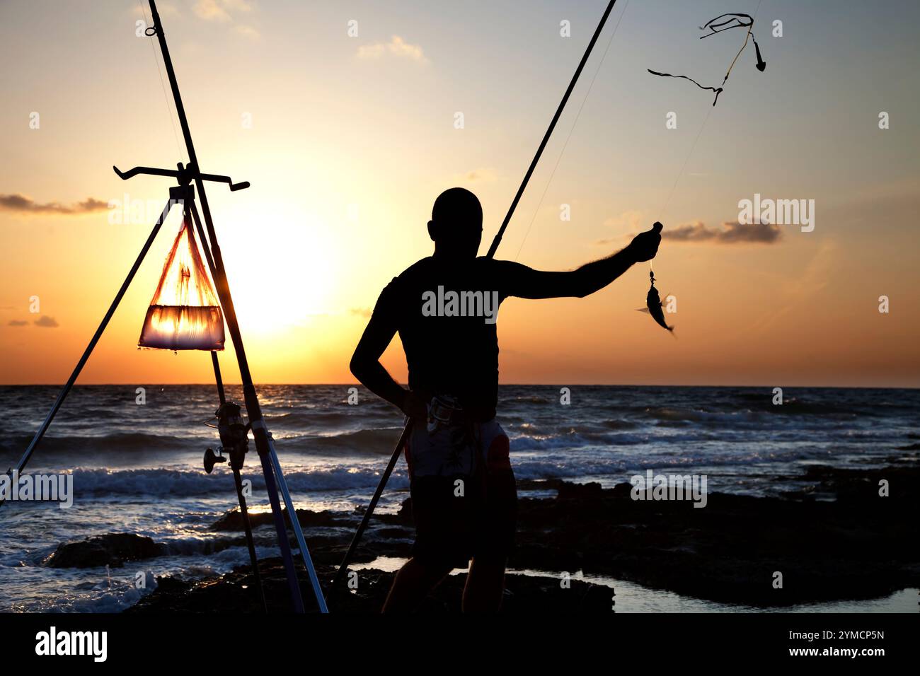 Fisherman silhouette catching a fish. Horizontal shot Stock Photo - Alamy