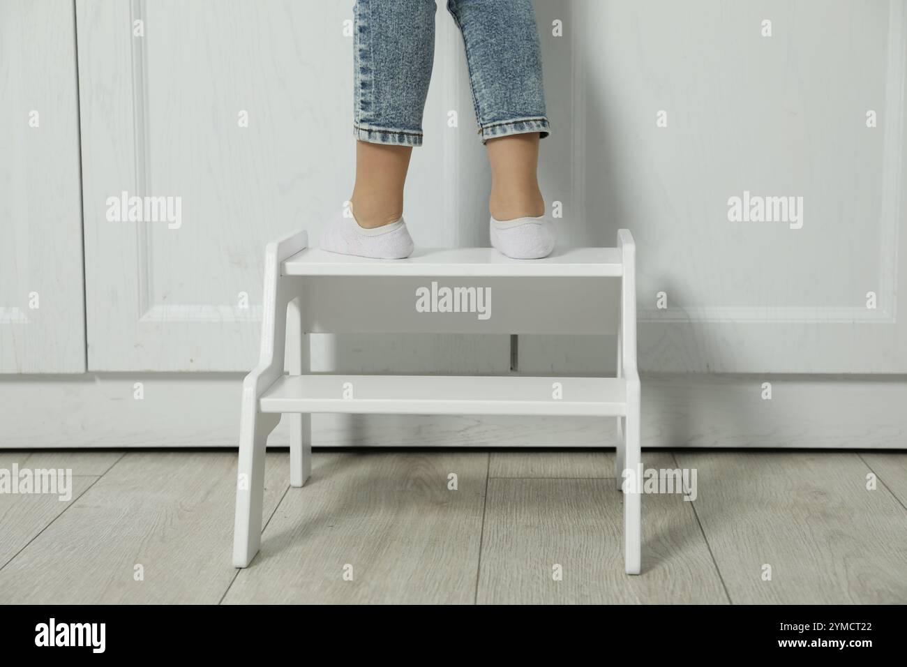 Little girl standing on step stool indoors, closeup Stock Photo - Alamy