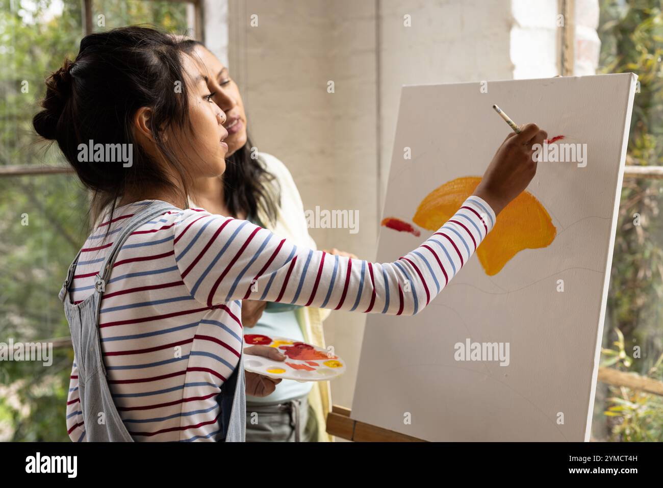 Asian female teenager painting on canvas at home with supportive ...