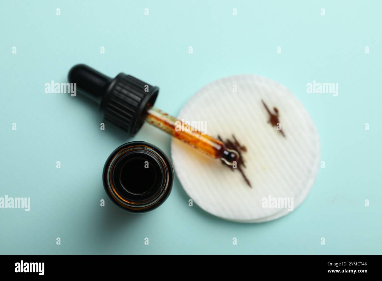 Bottle of topical iodine with dropper and cotton pad on light blue ...