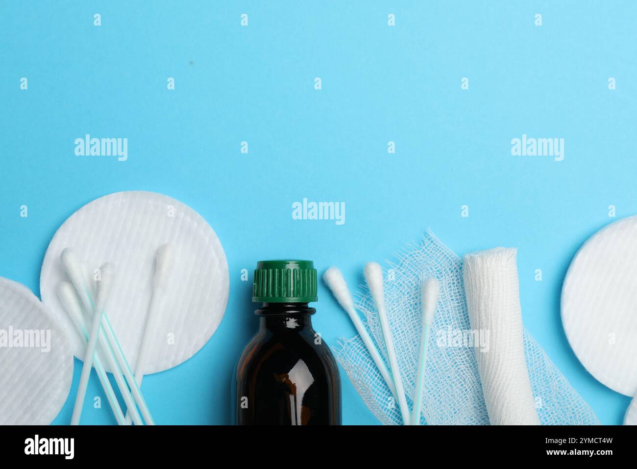 Topical iodine, bandage, cotton pads and swabs on light blue background ...