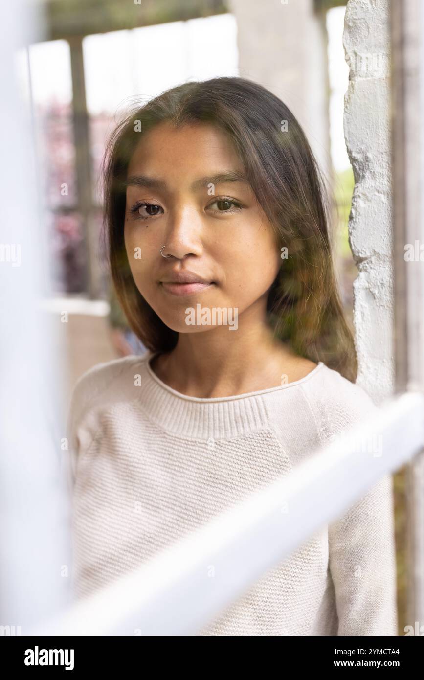 asian female teenager standing by window at home, looking thoughtful ...