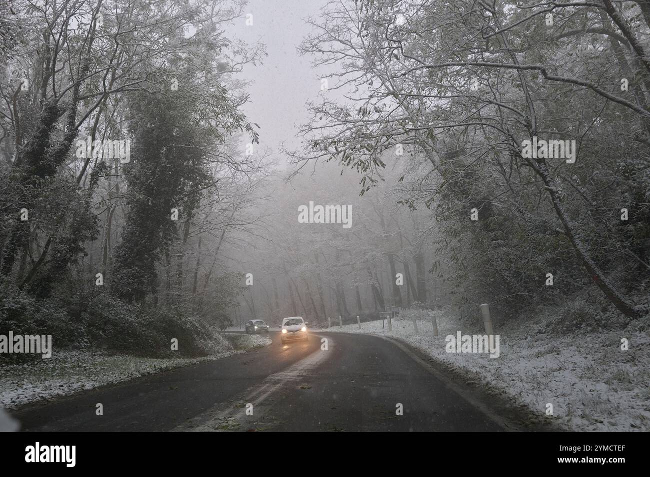 France. 21st Nov, 2024. Snow falls as vehicles drive along a road in ...