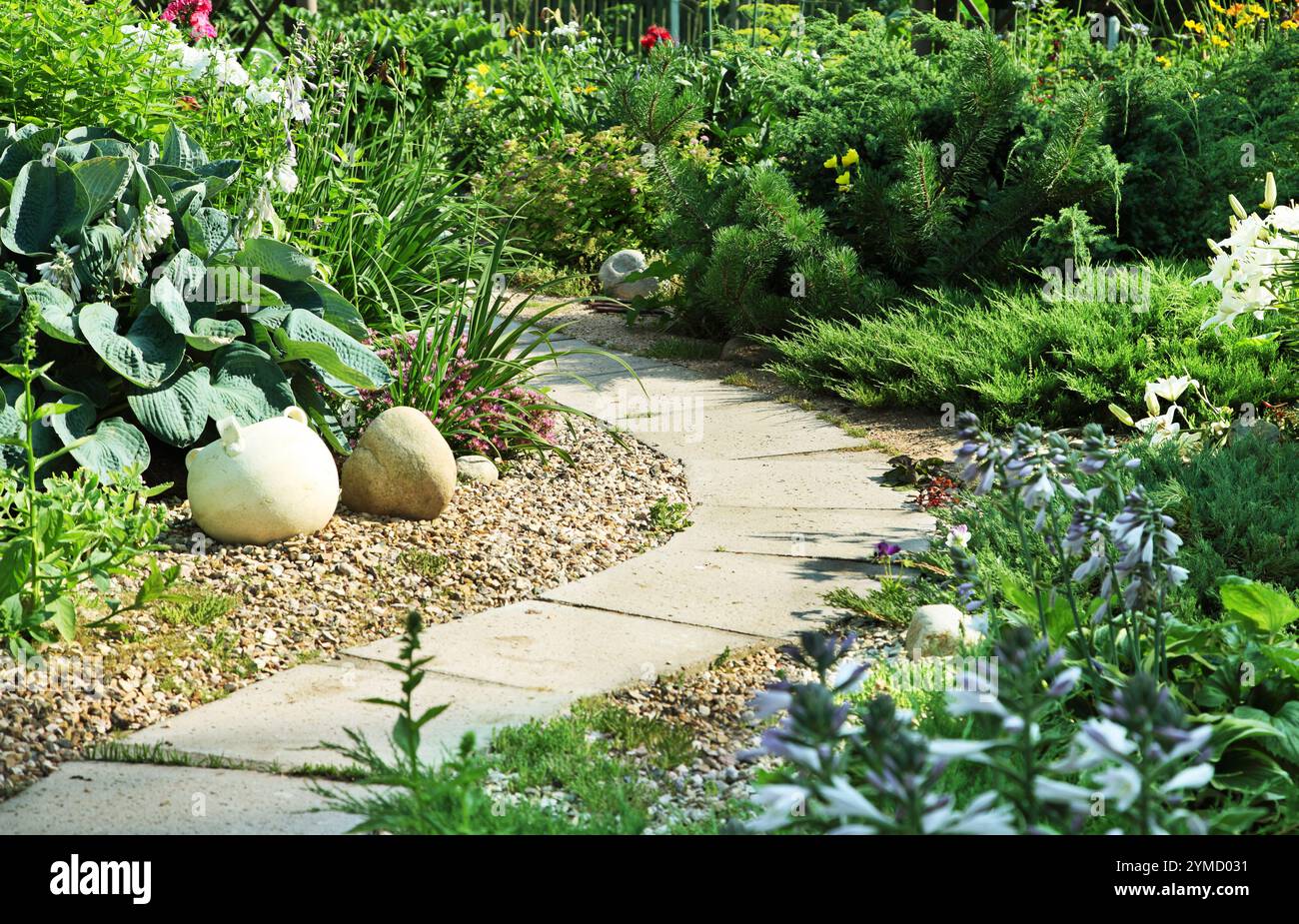 A stone walkway winding its way through a tranquil garden Stock Photo ...