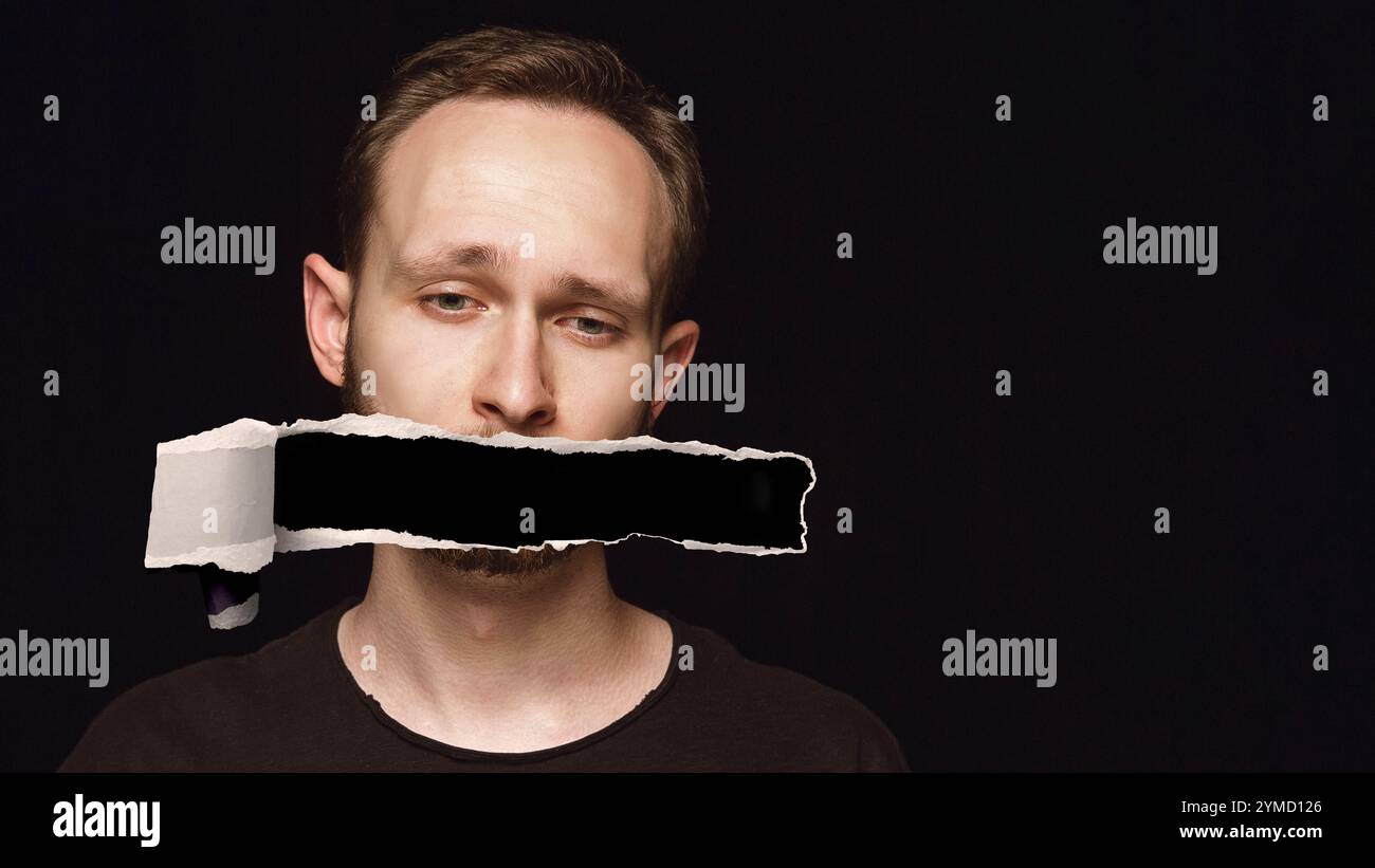 Sad man with torn paper covering his mouth, symbolizing restricted ...