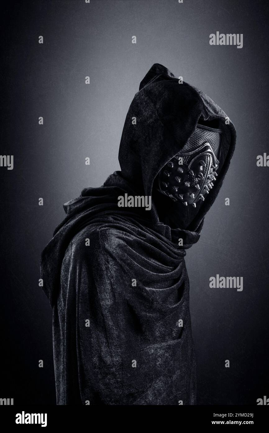 Scary figure in hooded cloak with spike studs mask at night over dark ...