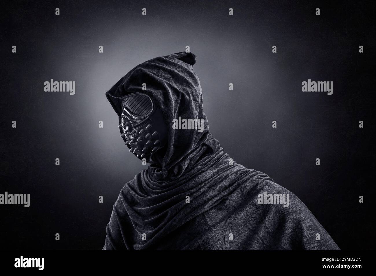 Scary figure in hooded cloak with spike studs mask at night over dark ...