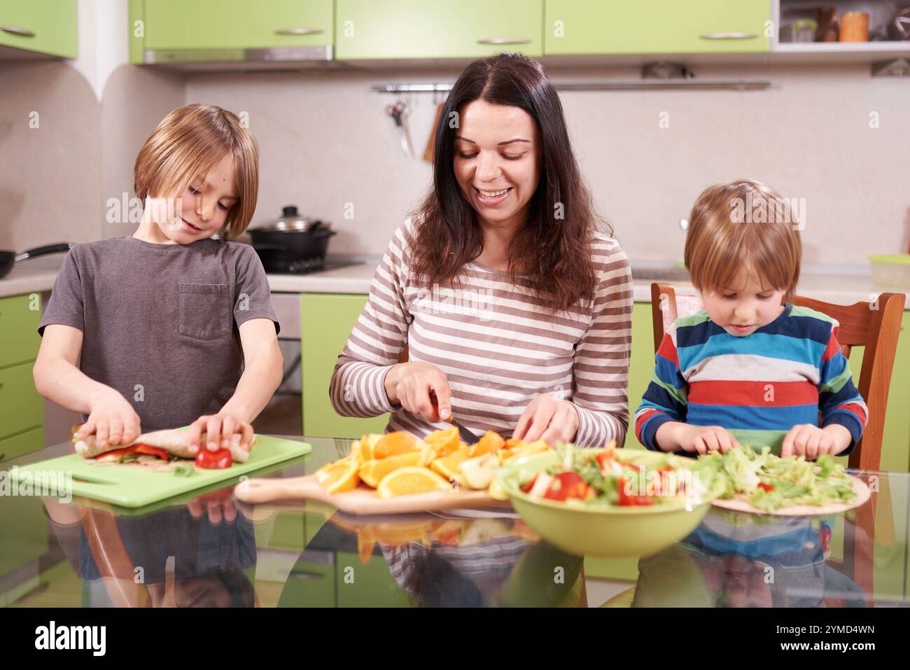 Happy family preparing healthy food in the kitchen, mother and children ...