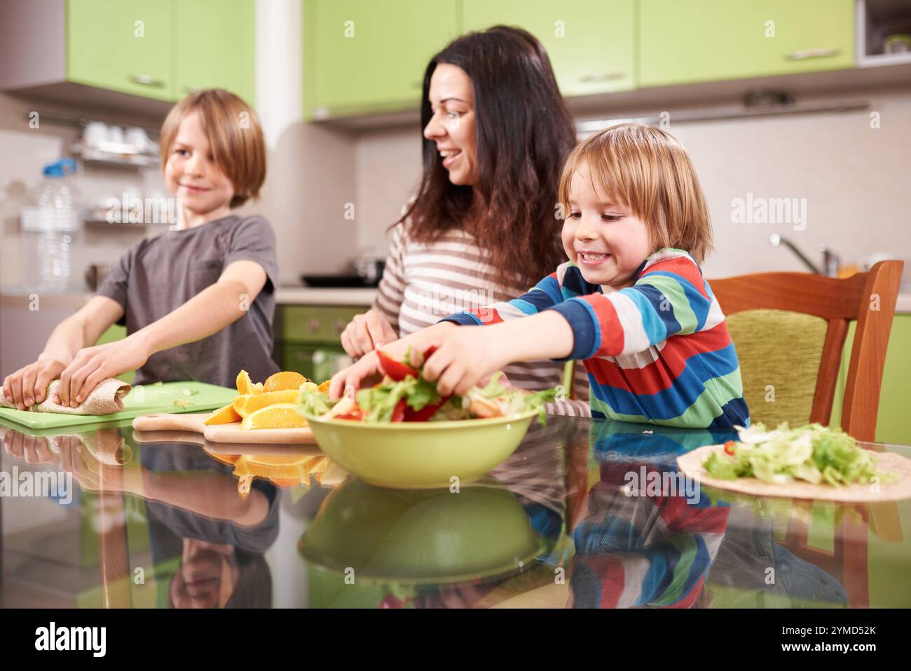 Happy family preparing healthy food in the kitchen, mother and children ...