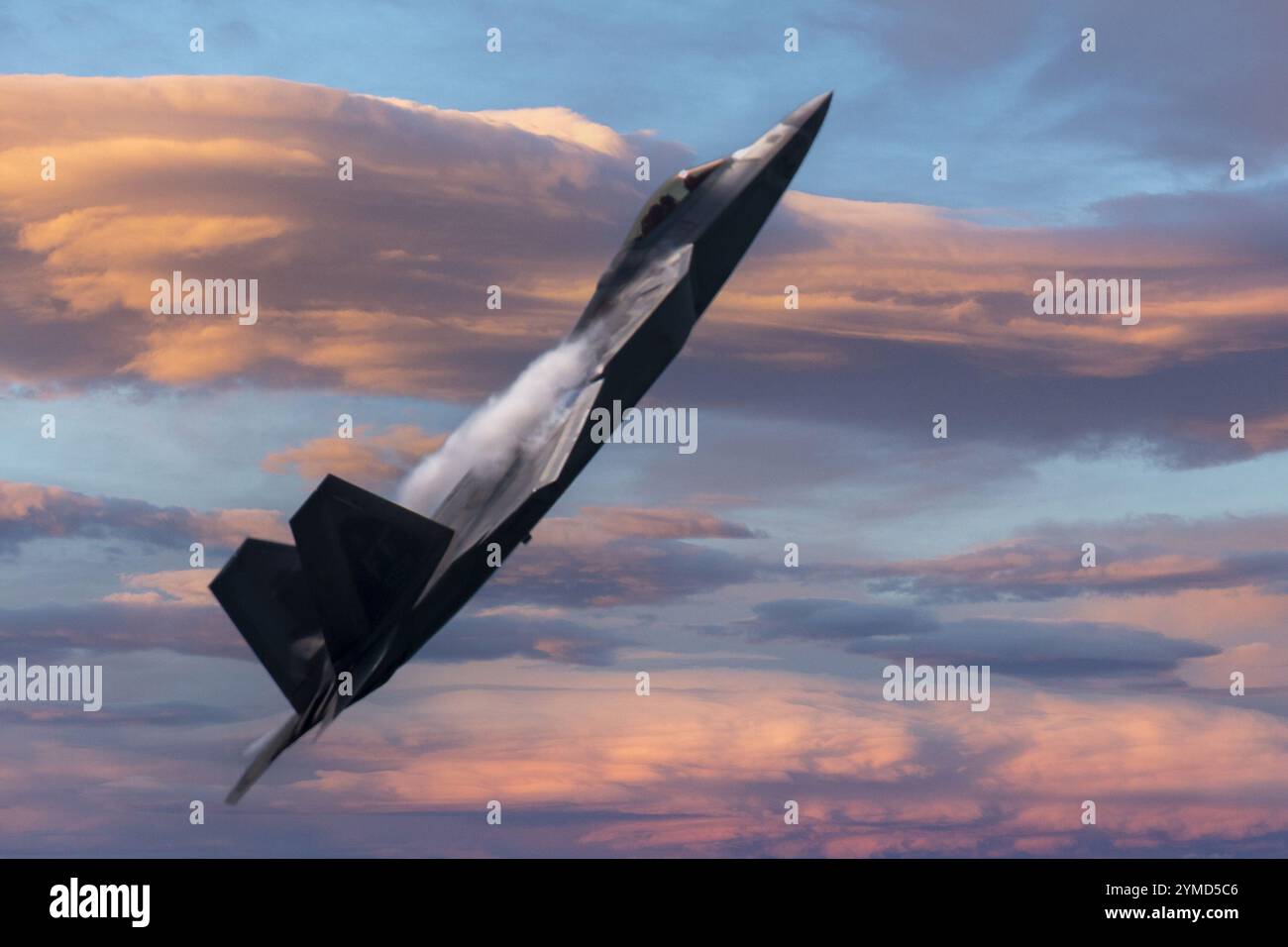 A fighter jet ascends rapidly, showcasing its agility against a vibrant ...