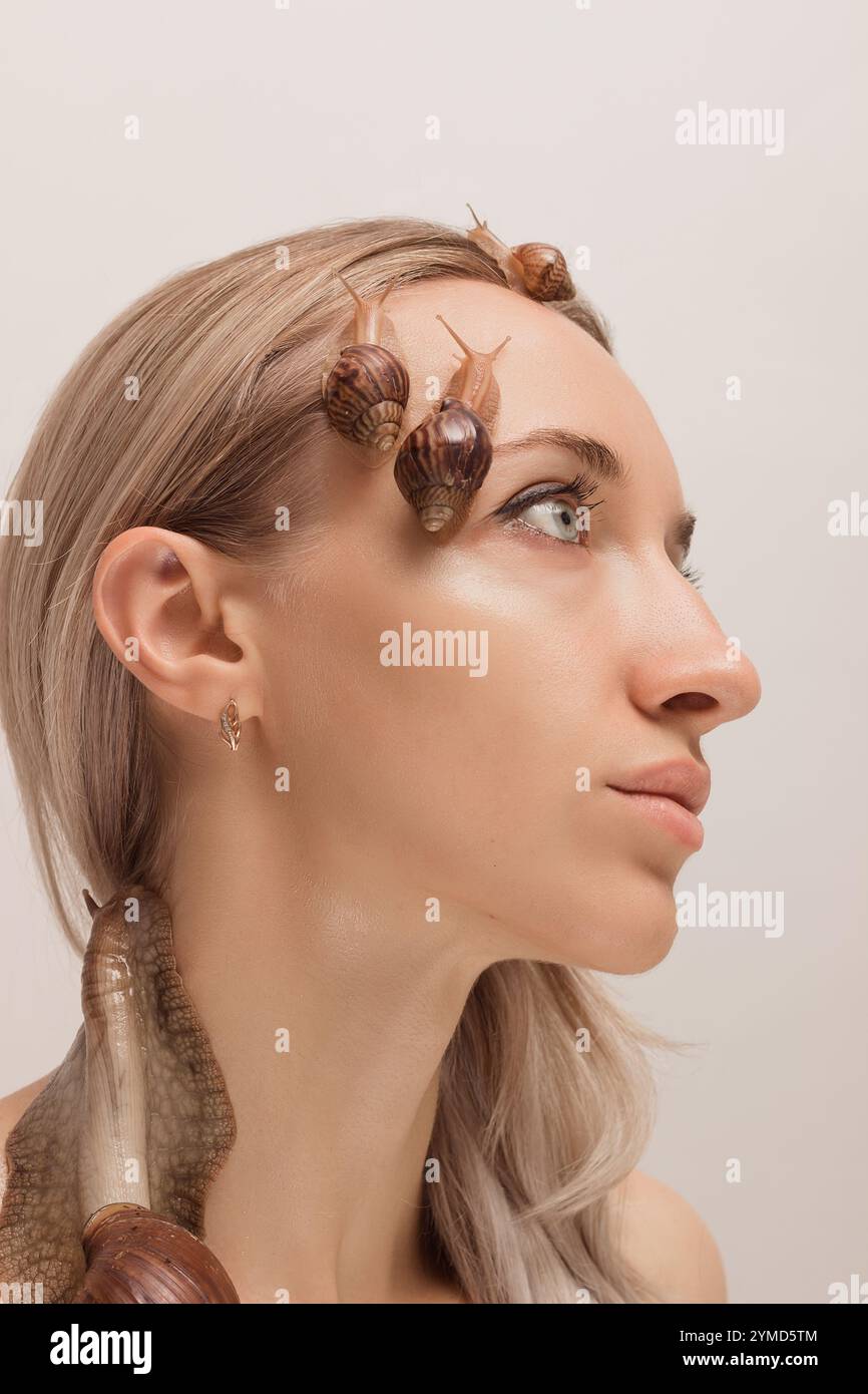 Beautiful young woman with snails on her face. Rejuvenation procedures ...