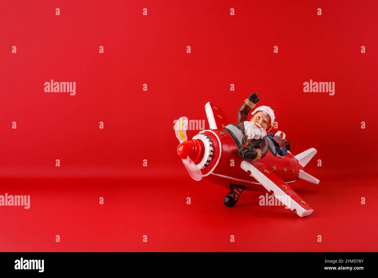 a festive figurine of Santa Claus riding a red toy airplane. background ...