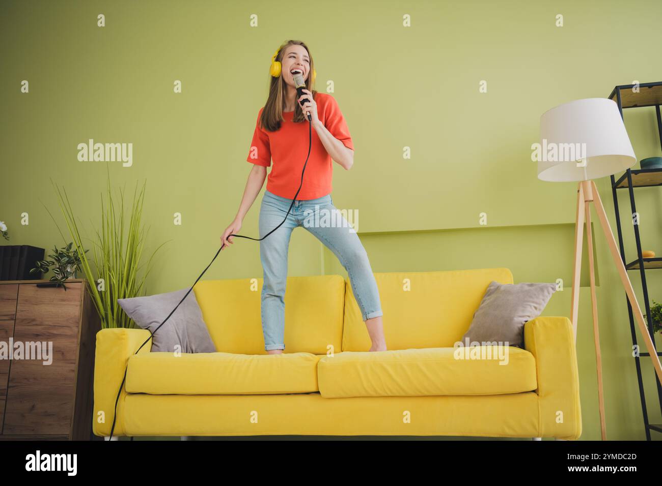 Full length photo of lovely young girl dance sofa sing karaoke dressed ...