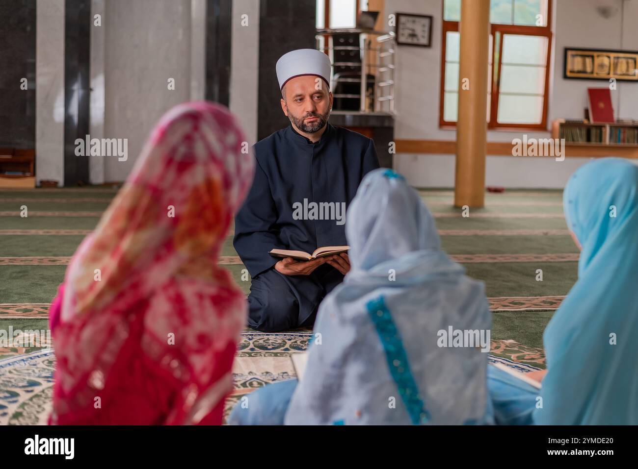 A Muslim teacher teaches child girl to read a holy book Quran inside ...