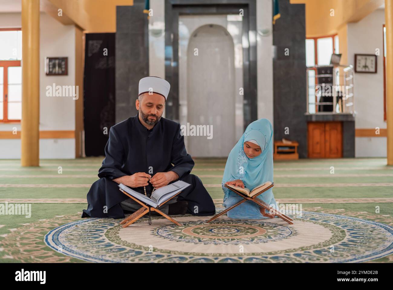 A Muslim teacher teaches child girl to read a holy book Quran inside ...