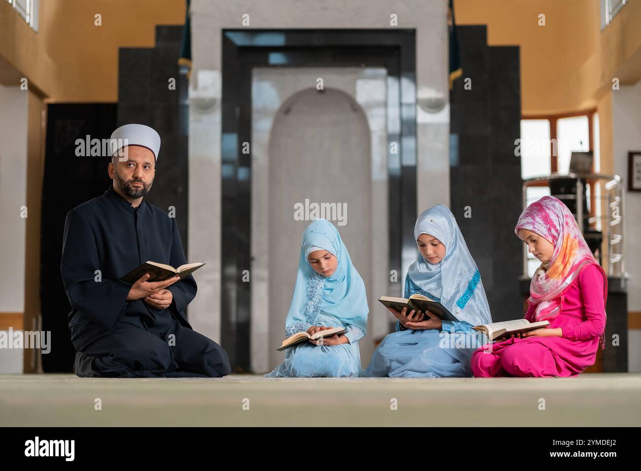 A Muslim teacher teaches children girls to read a holy book Quran ...