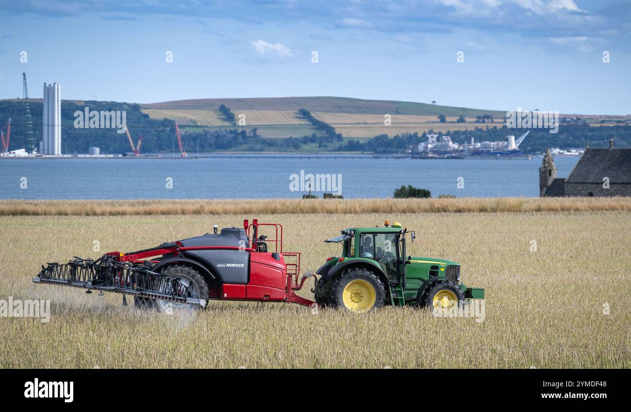 Farmer spraying an arable crop with a tractor and trailed sprayer ...