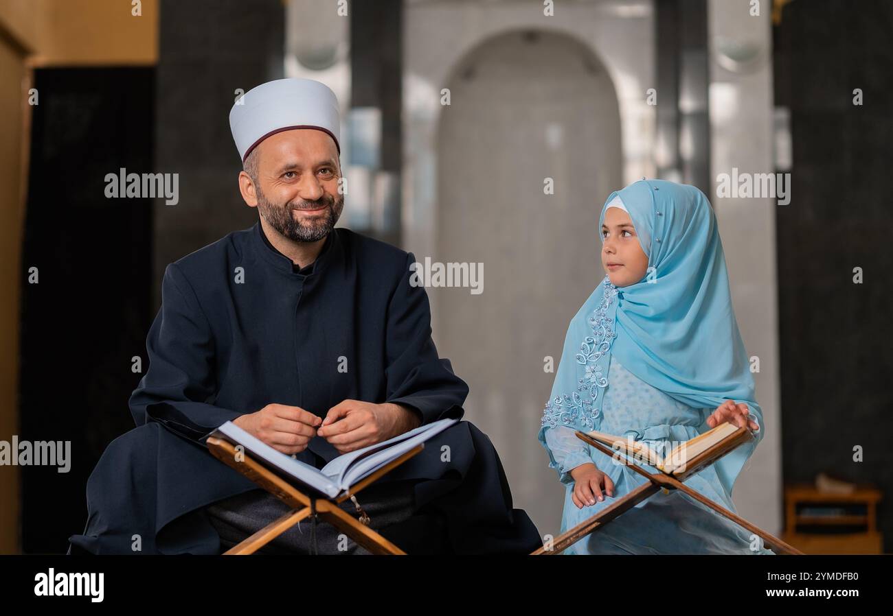 A Muslim teacher teaching child girl to reading a holy book Quran ...