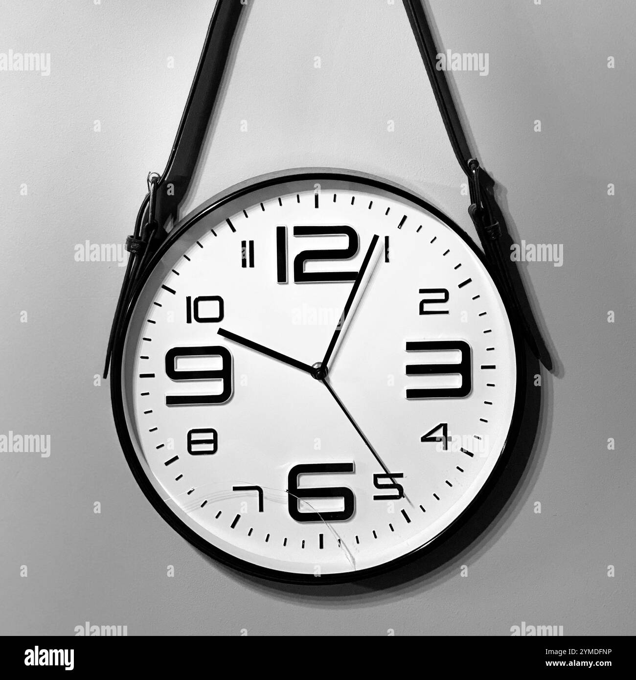 The image shows a black and white wall clock with large, bold numbers ...
