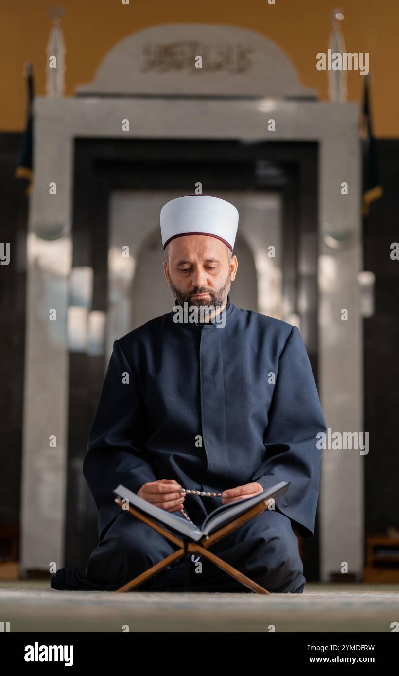 A Muslim prayer man praying while reading a Quran inside the mosque ...