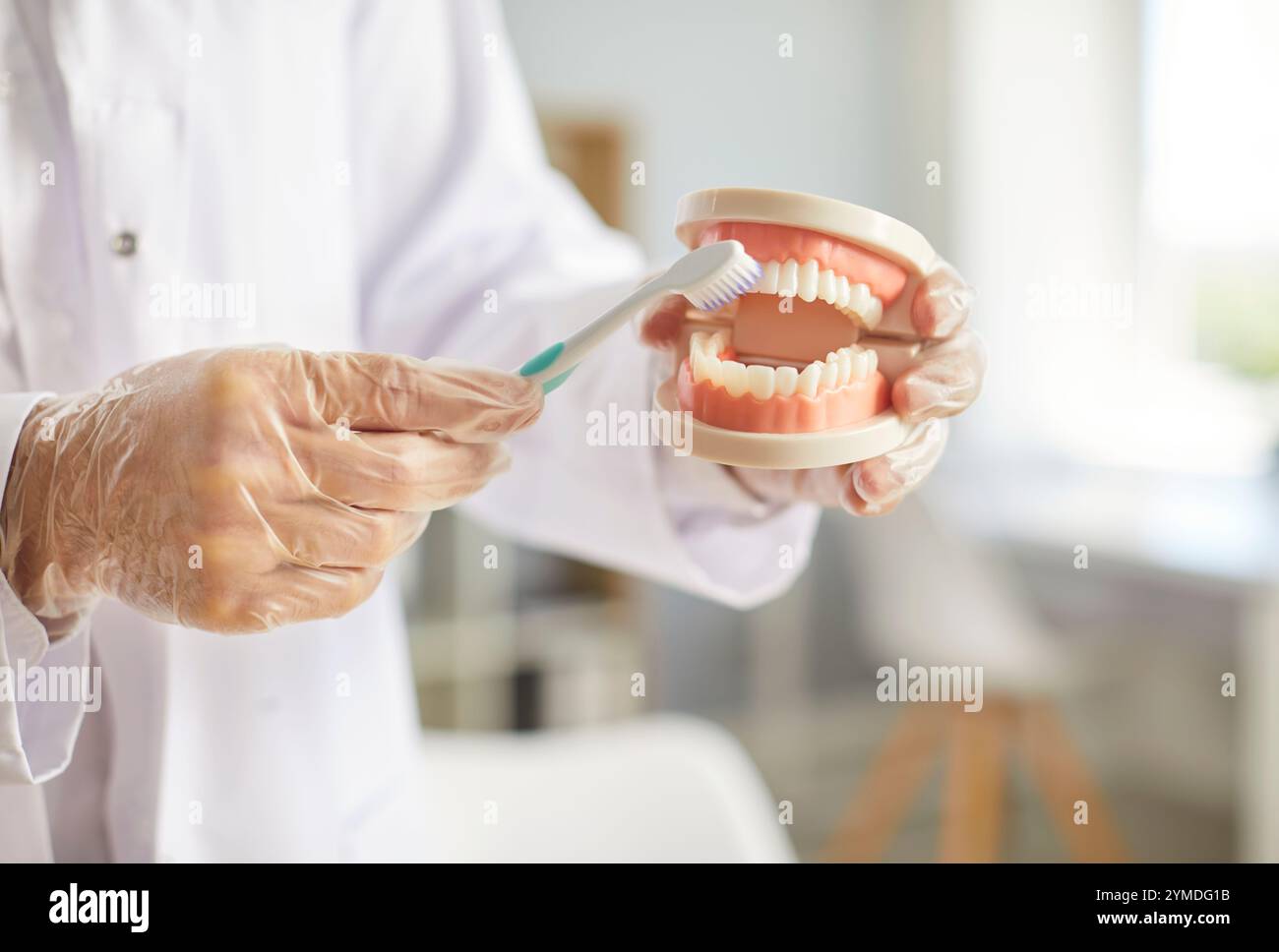 Professional hygienist holding a denture and showing how to brush teeth ...