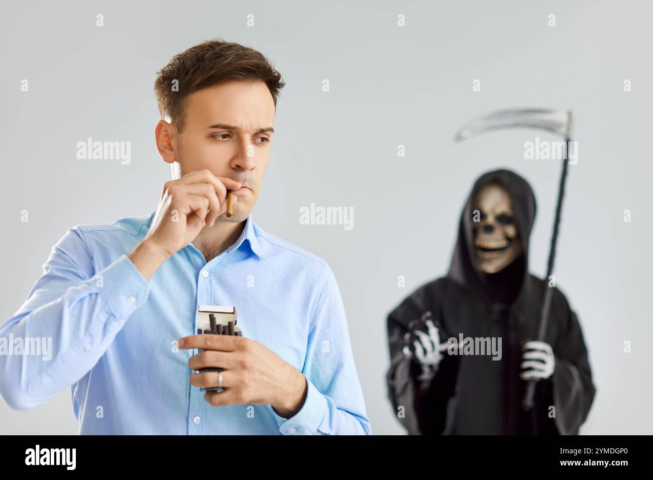 Man smoking cigarette with a grim reaper holding scythe standing behind ...
