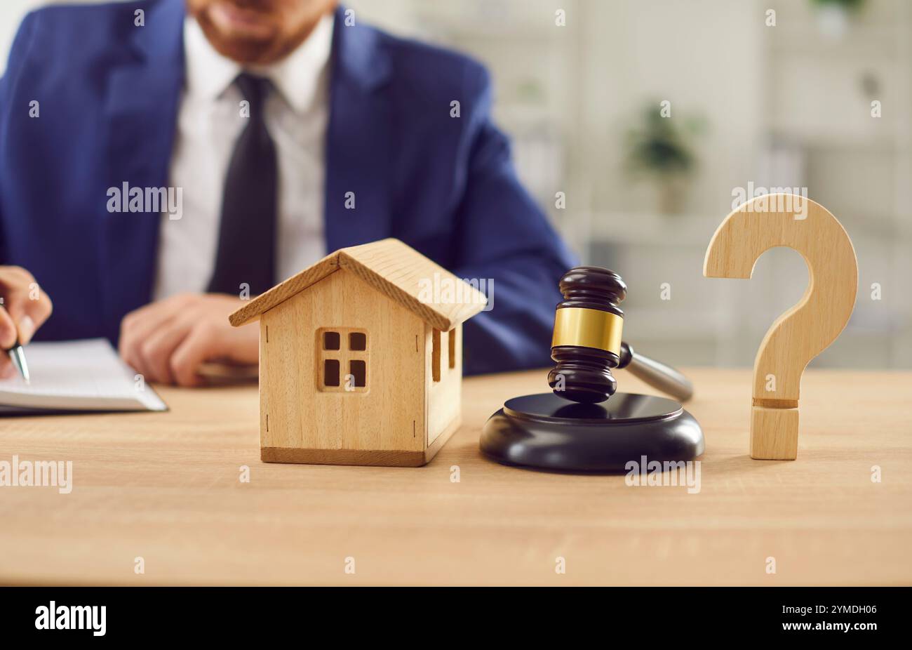 Judge gavel, wooden house and question mark standing at desk with a ...