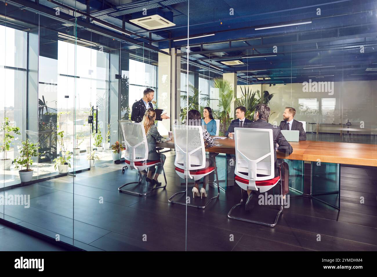 Group of business people behind closed glass doors sit in a meeting ...
