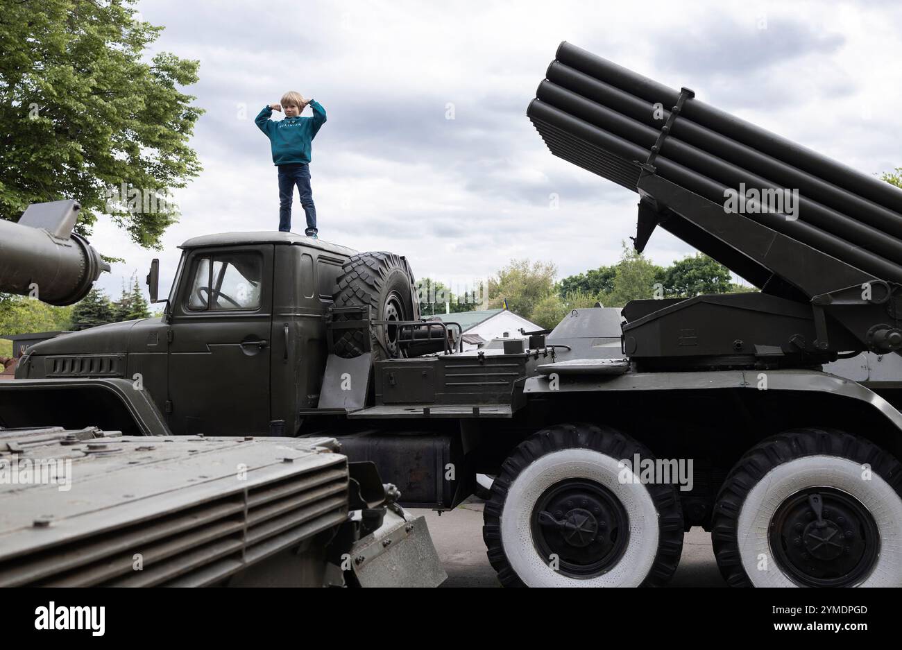 young boy stands on top of cockpit of military armored vehicle ...
