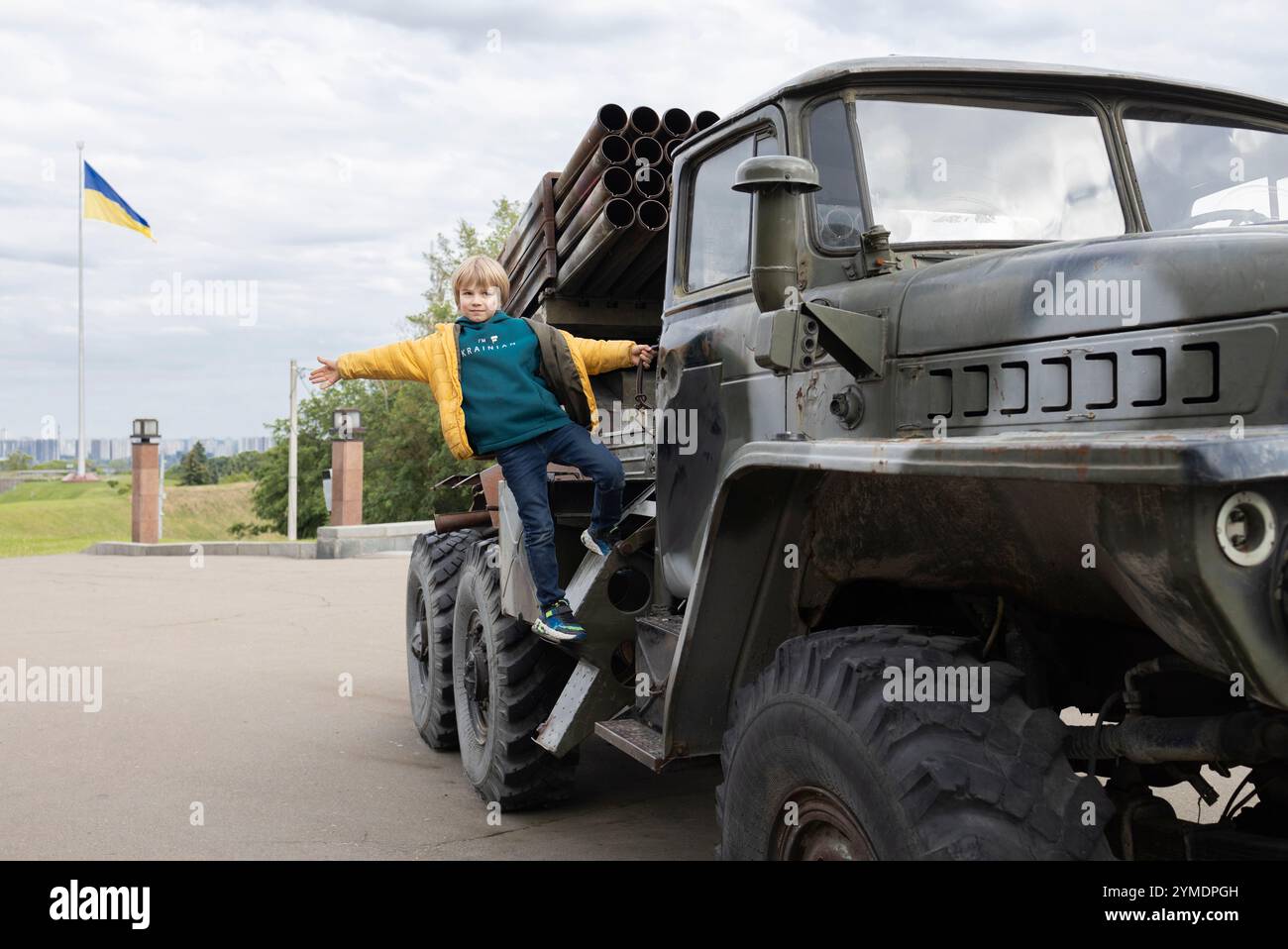 boy stands on step of military armored vehicle, multiple launch rocket ...