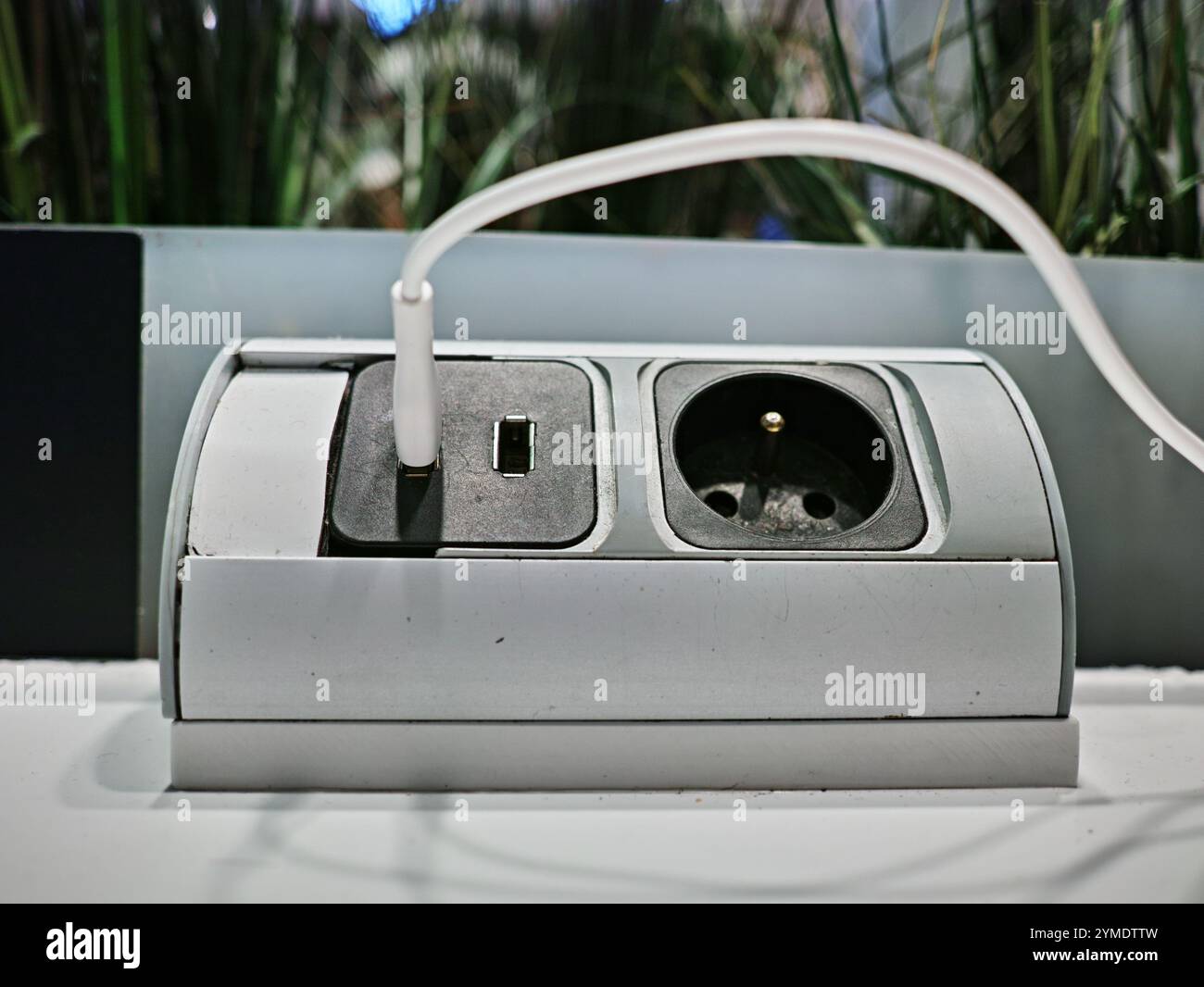 A white electrical outlet with a black cord coming out of it. The ...