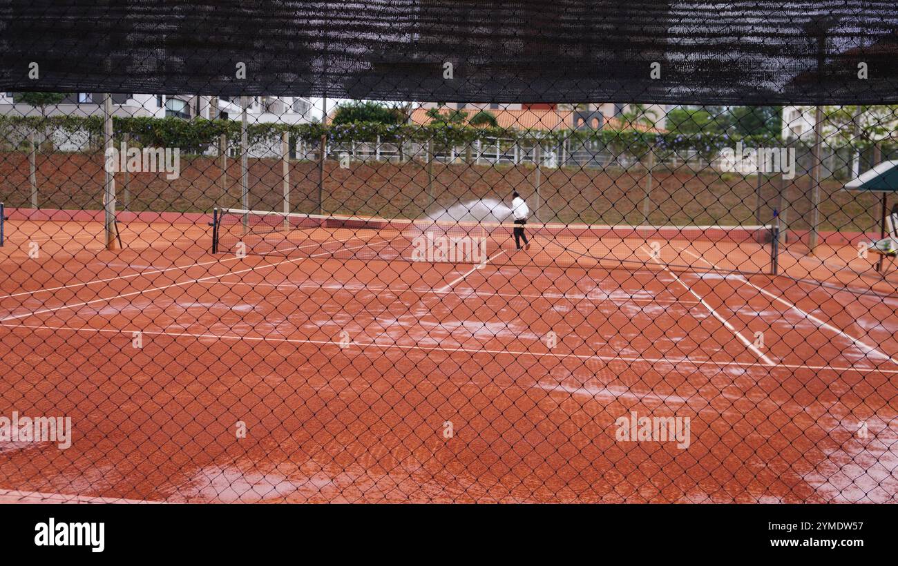 Man throwing water on a clay tennis court Stock Photo - Alamy