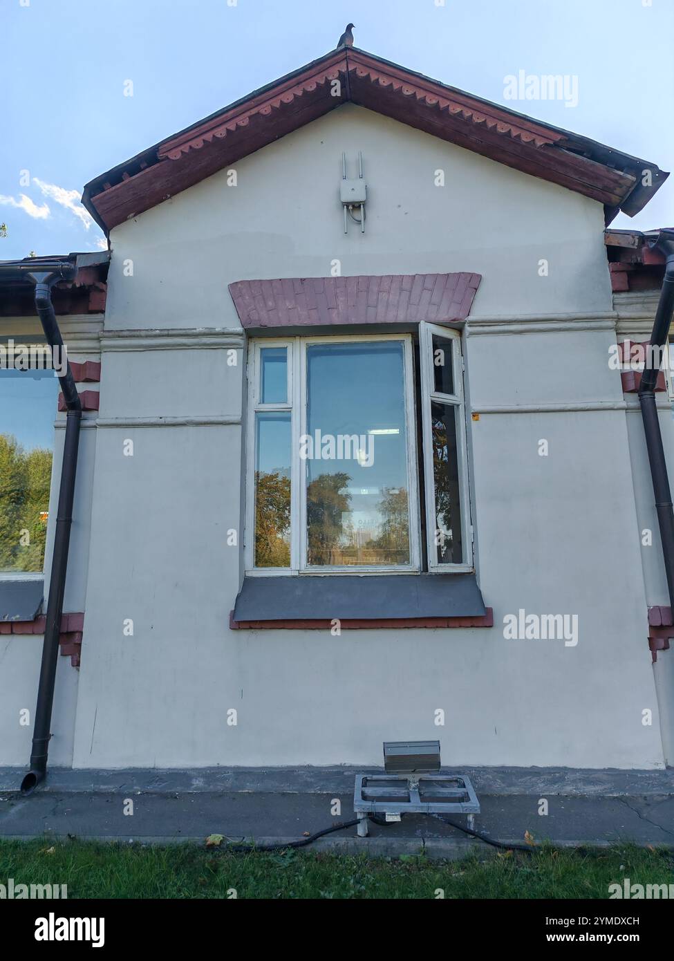 A traditional building with red accents and a tall, sloped roof, framed ...