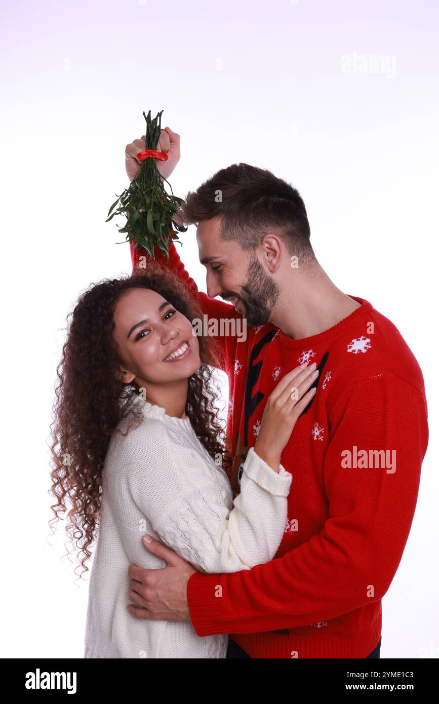 Lovely couple under mistletoe bunch on white background Stock Photo - Alamy