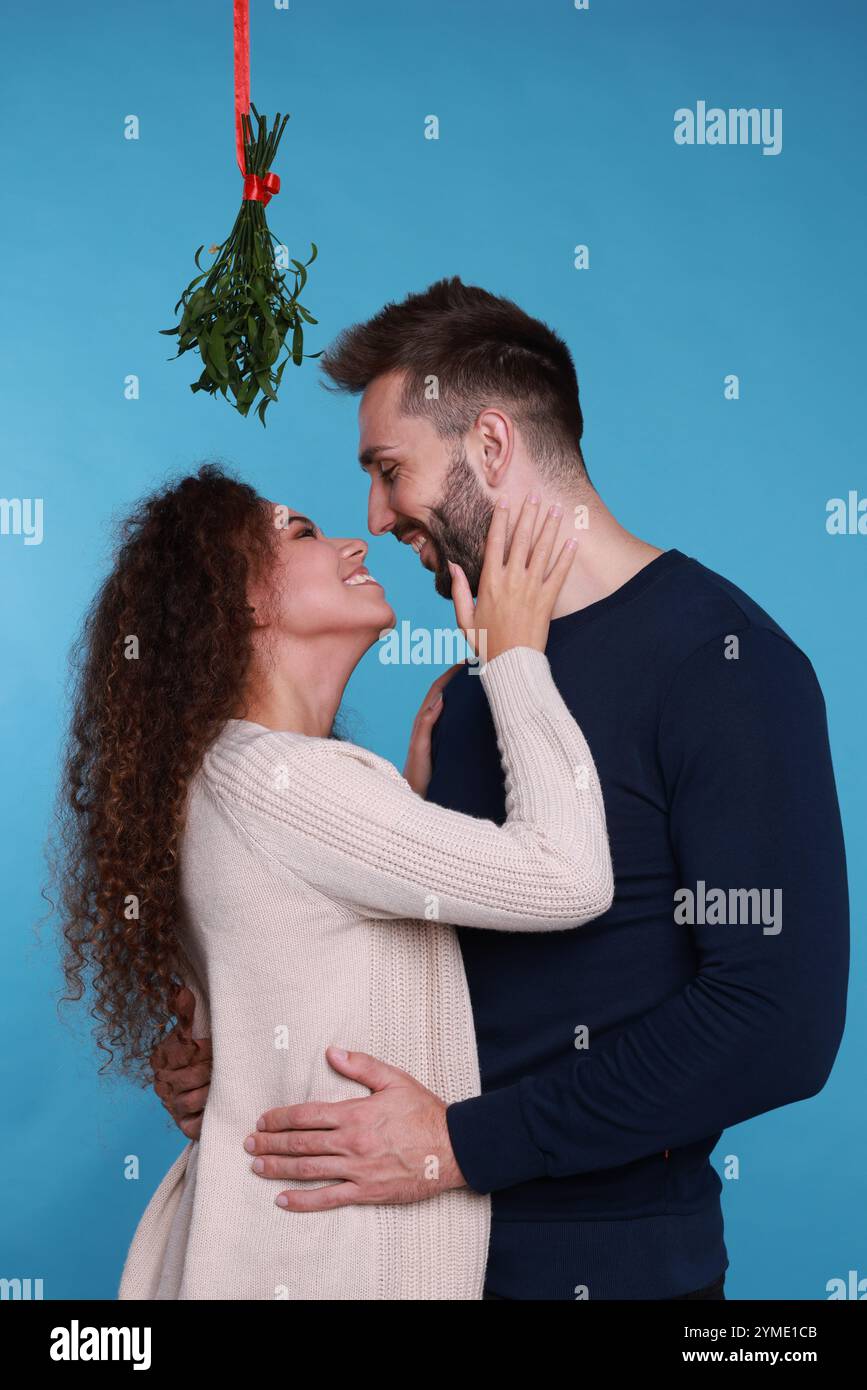 Lovely couple under mistletoe bunch on light blue background Stock ...