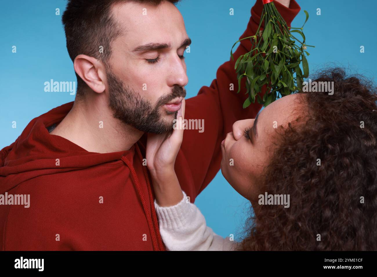 Lovely couple under mistletoe bunch on light blue background Stock ...