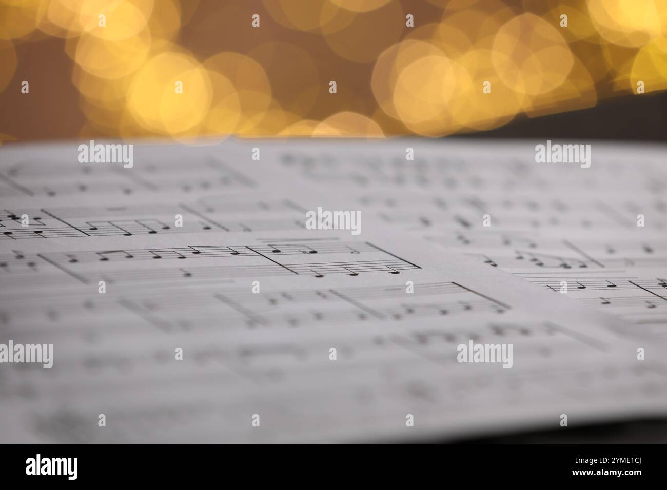 Sheet of musical notes against blurred lights, closeup. Bokeh effect ...