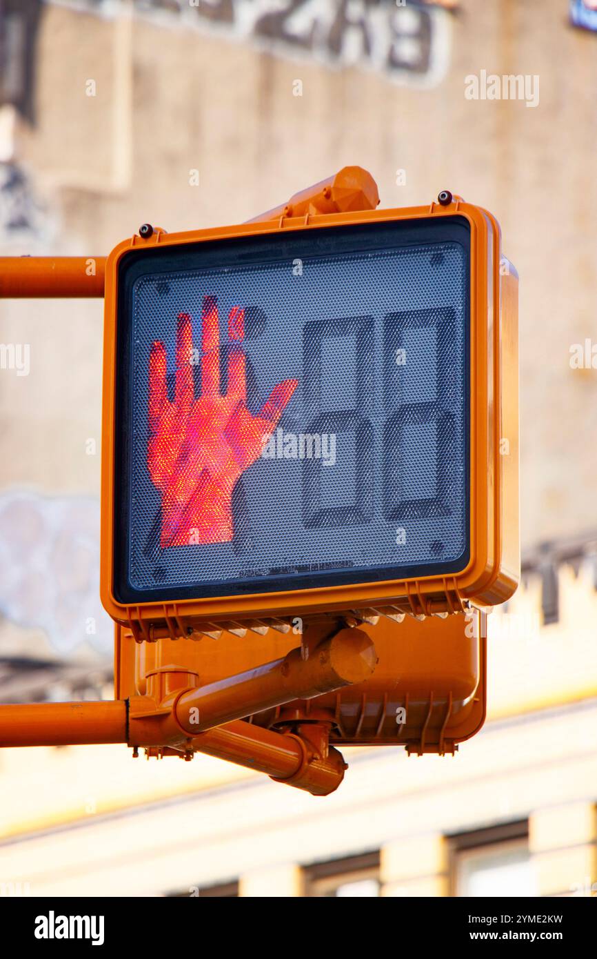 Urban traffic signal with a red hand indicating stop against a blurred ...
