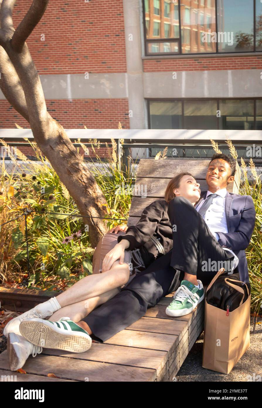 A young mixed race couple embrace on a stylish wooden bench on the ...