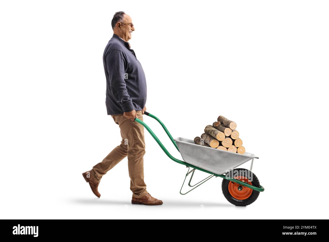 Full length profile shot of a mature man pushing a wheelbarrow with ...