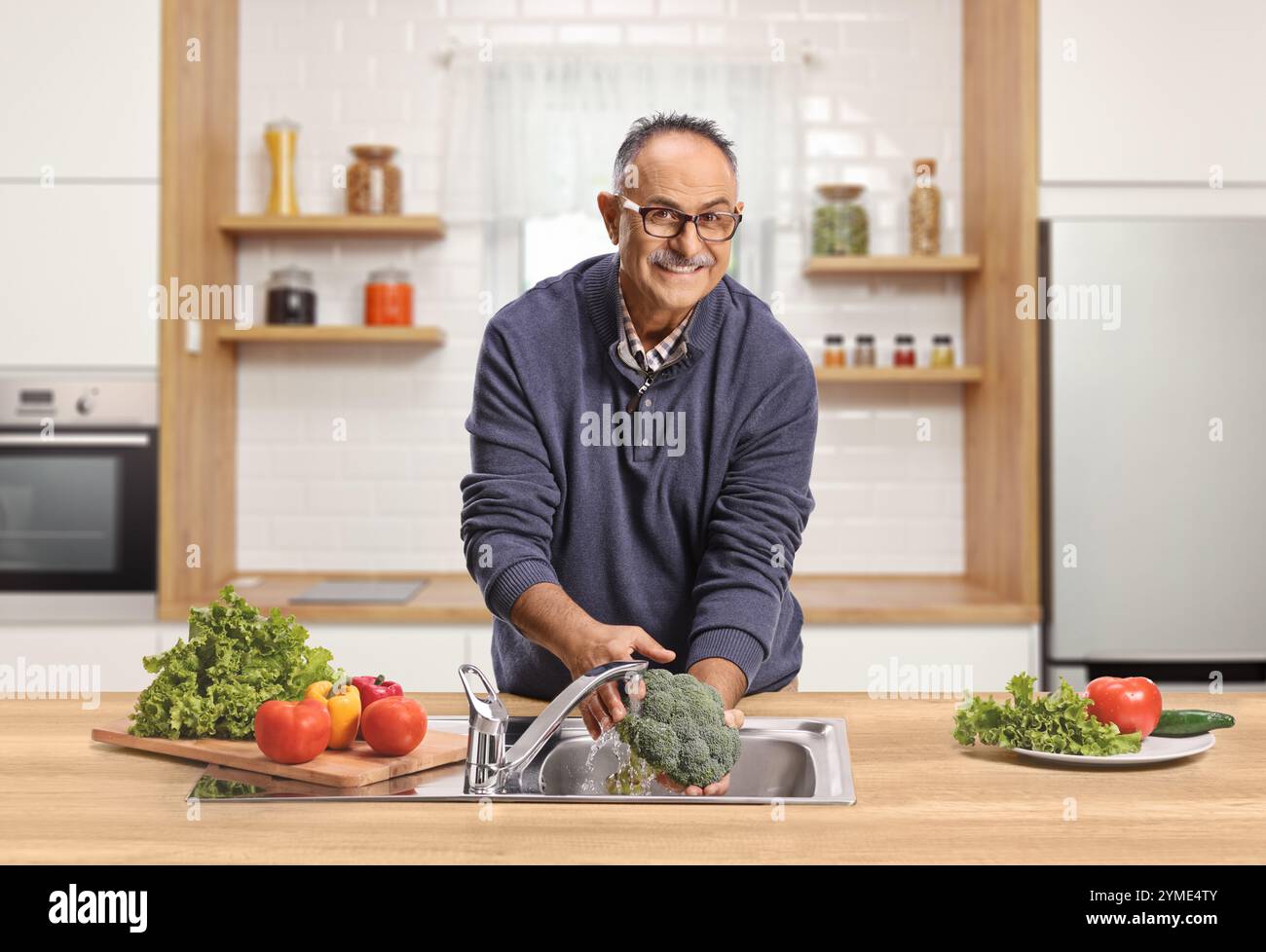 Man washing broccoli and vegetables in a kitchen Stock Photo - Alamy