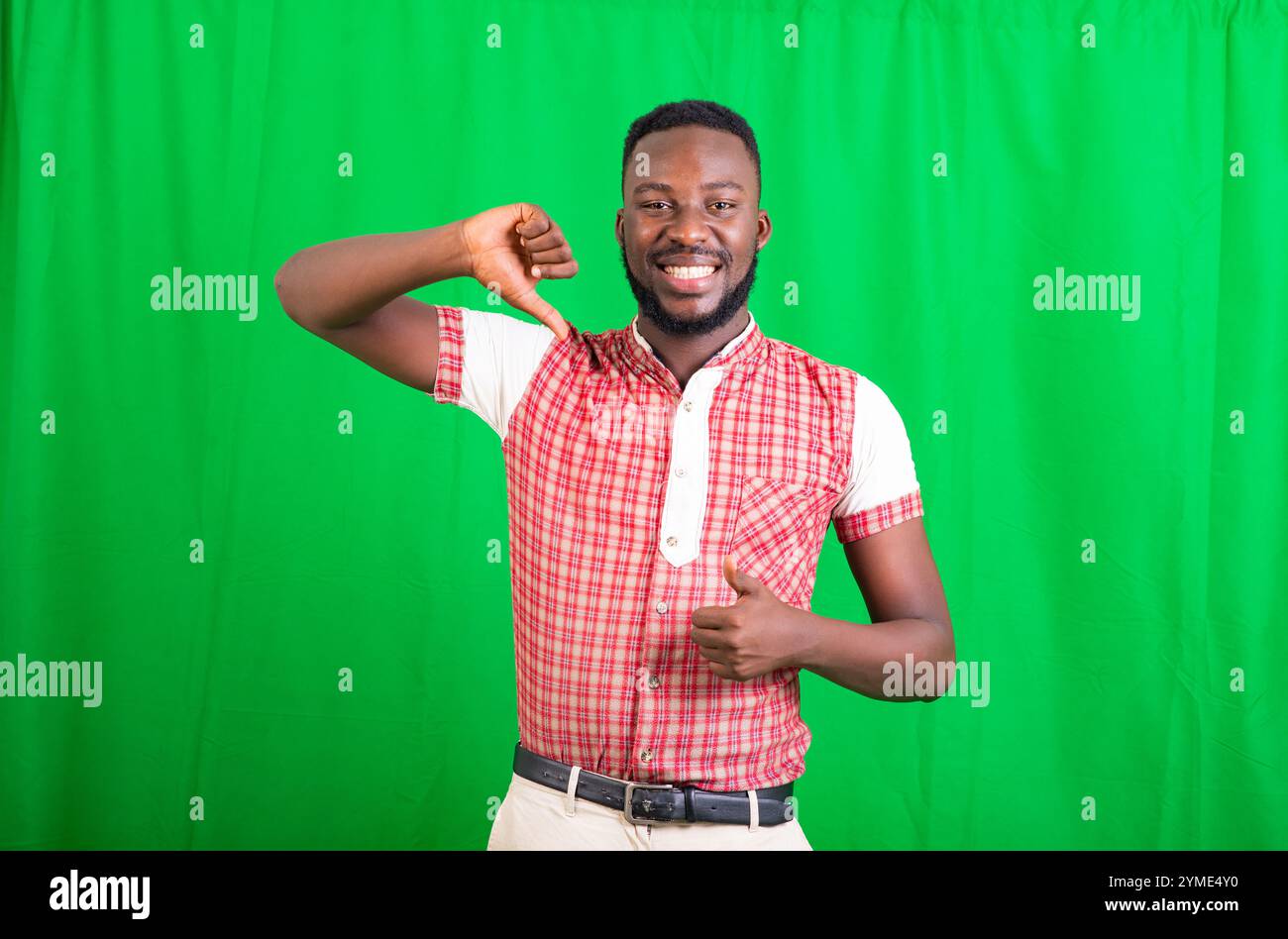portrait of a handsome young man smiling and pointing thumbs up and ...