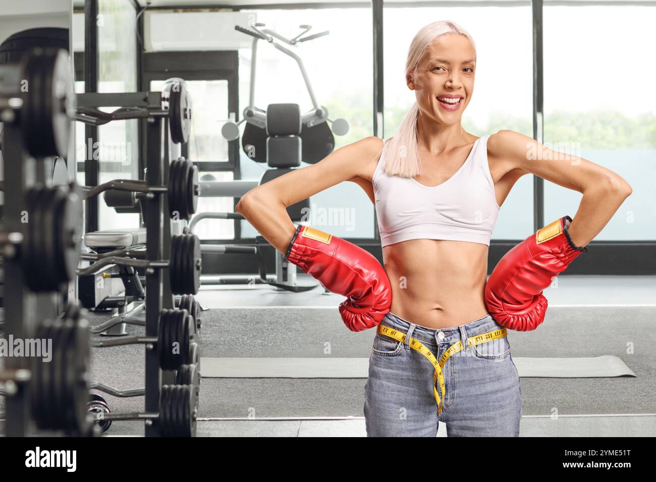 Slim woman with measure tape and boxing gloves standing in a gym Stock ...