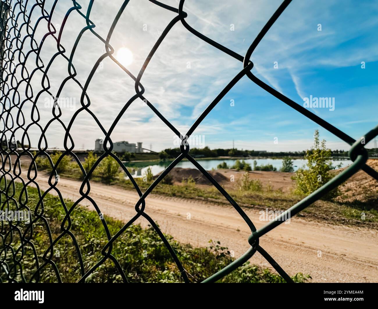 A chain link fence with a view of a lake and a building in the ...