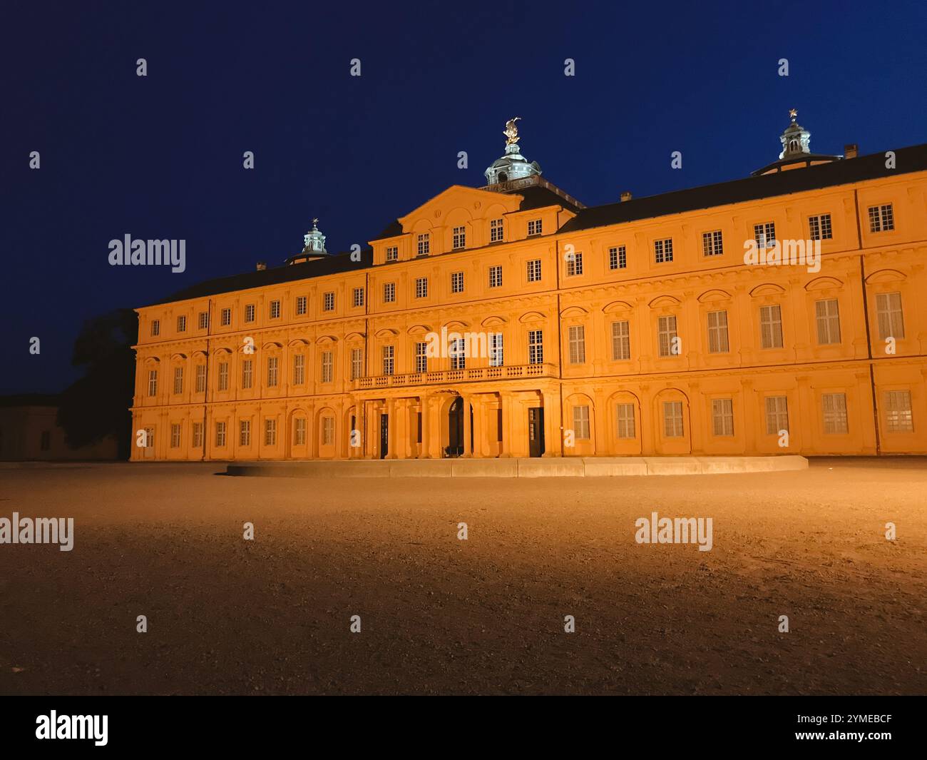 A large building with a yellow facade is lit up at night. The building ...