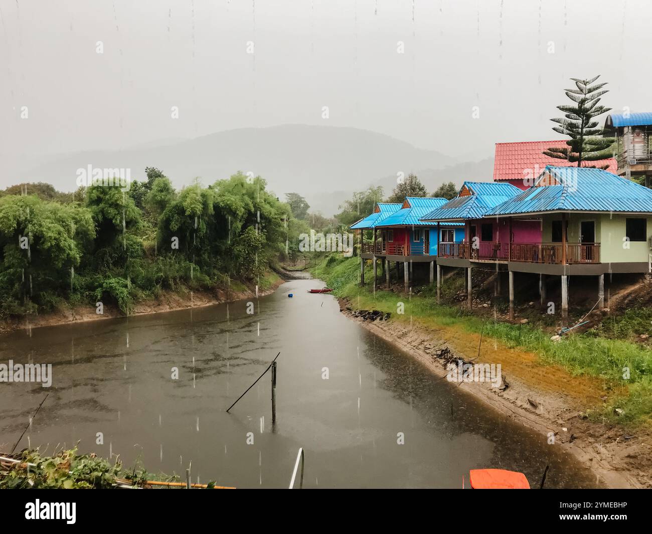 A river with a bridge and houses on the other side. The sky is cloudy ...