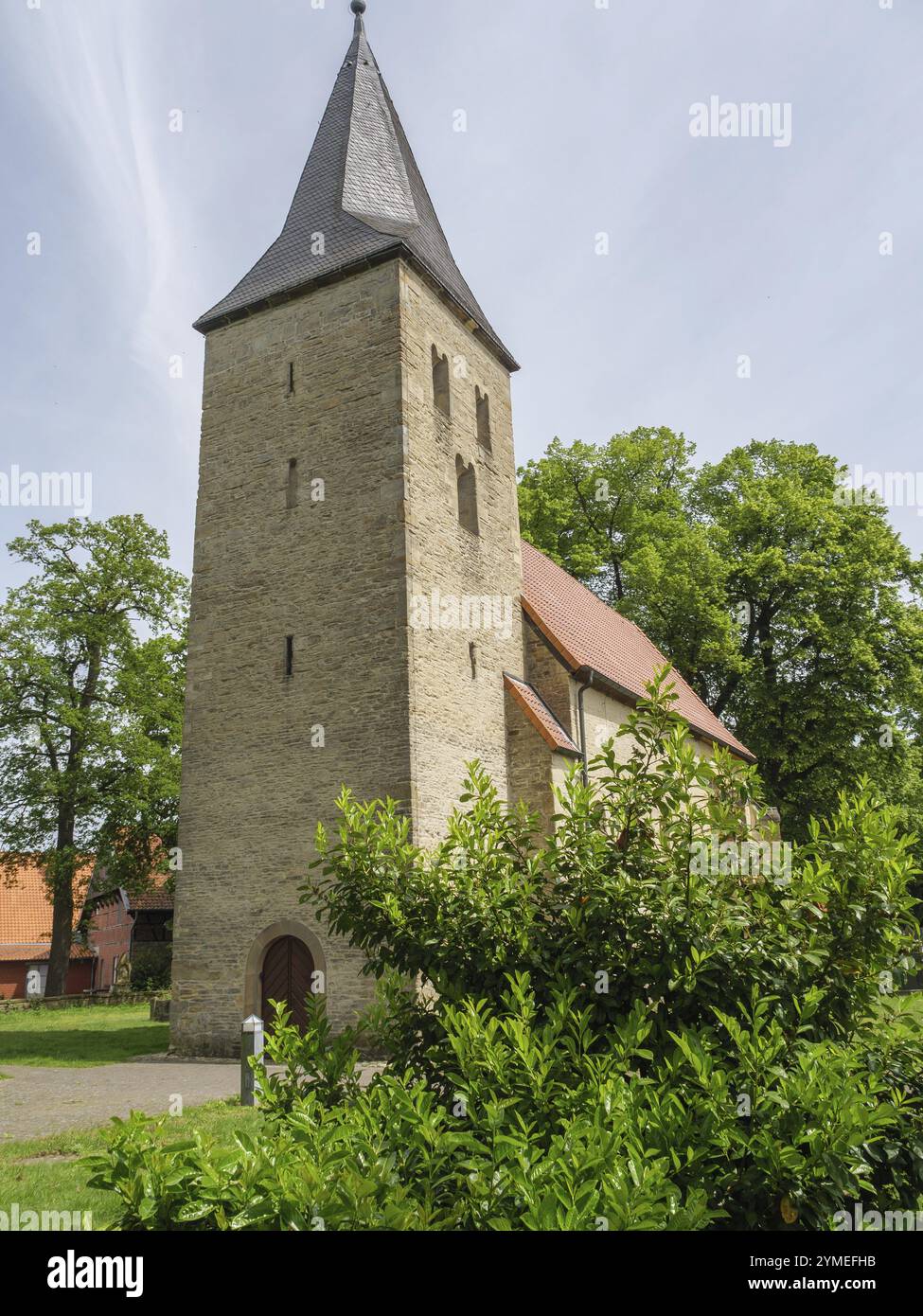 A tall Gothic brick church tower surrounded by trees and nature ...